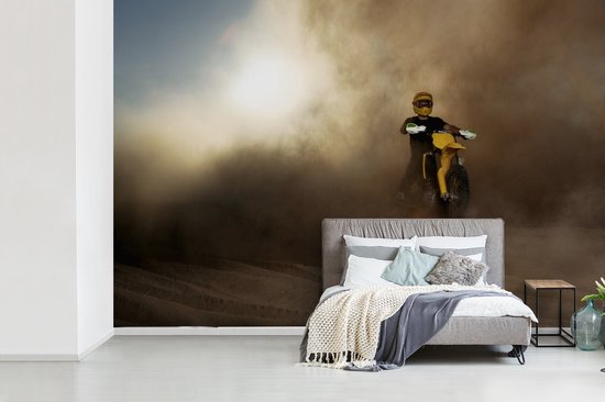 Behang - Fotobehang Een man op een gele motor in een stofwolk - Breedte ...