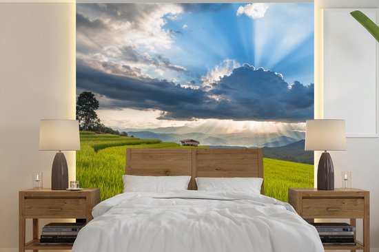 Behang - Fotobehang Zonnestralen bij een zonsondergang over het ...