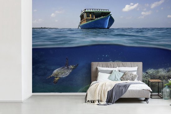 Behang - Fotobehang Een zeeschildpad naast een koraalrif onder een boot ...