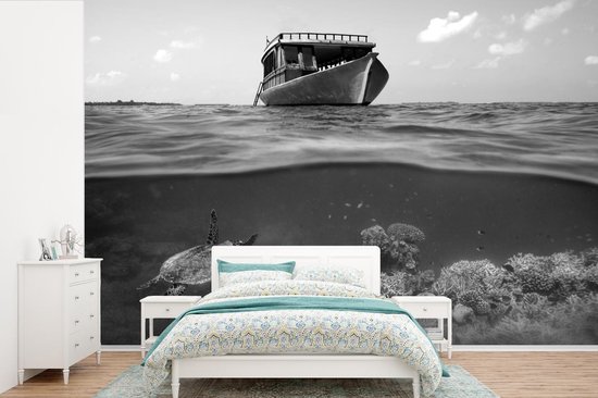 Behang - Fotobehang Een zeeschildpad naast een koraalrif onder een boot ...
