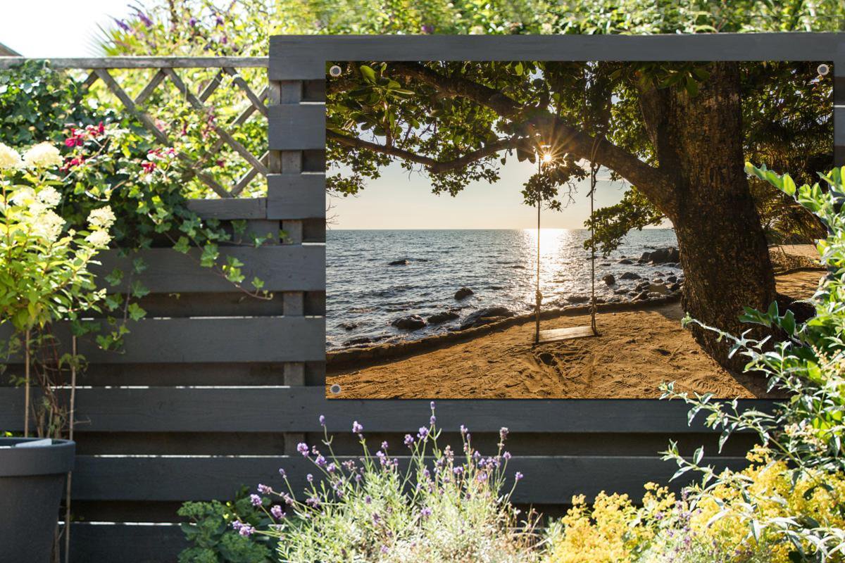 Tuinposter - Tuindoek - Tuinposters buiten - Een tropische boom met schommel bij het... | bol.com