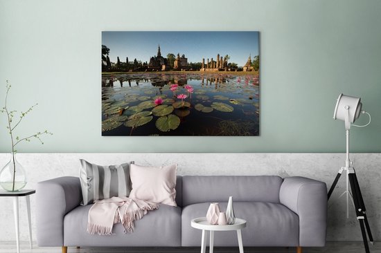 Canvas Schilderij Foto van mooie waterlelies in het water met op de achtergrond de... | bol