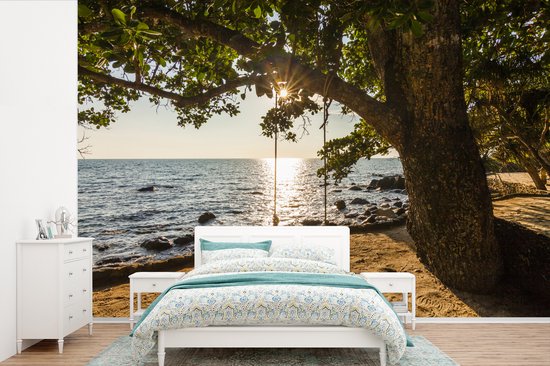 Behang - Fotobehang Een tropische boom met schommel bij het strand van Ko Chang -... | bol